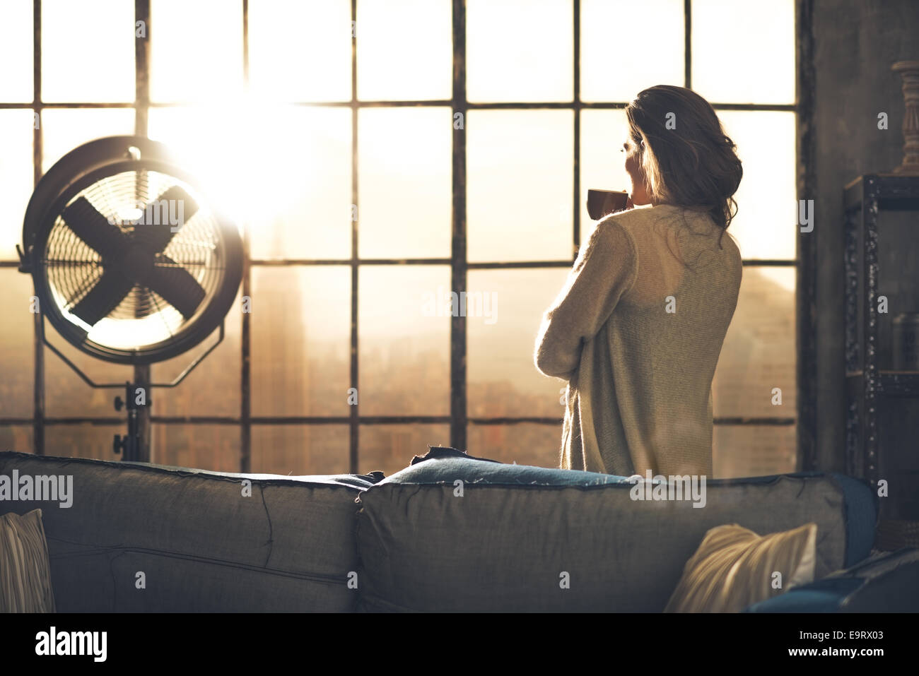 Young woman enjoying cup of coffee in loft apartment. rear view Stock ...