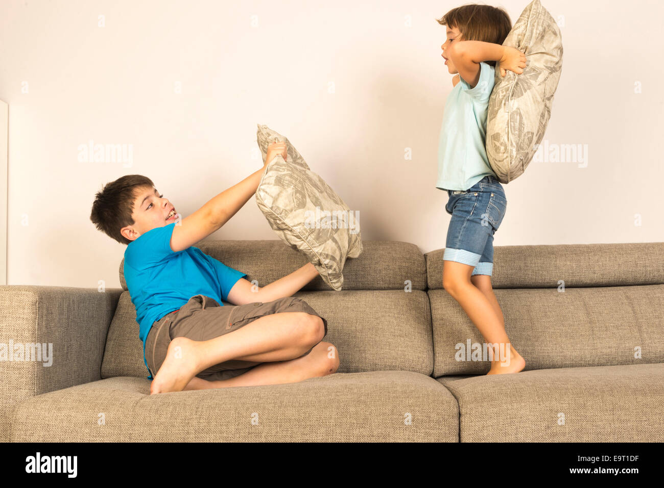 Children fighting together with pillows on sofa at home Stock Photo - Alamy