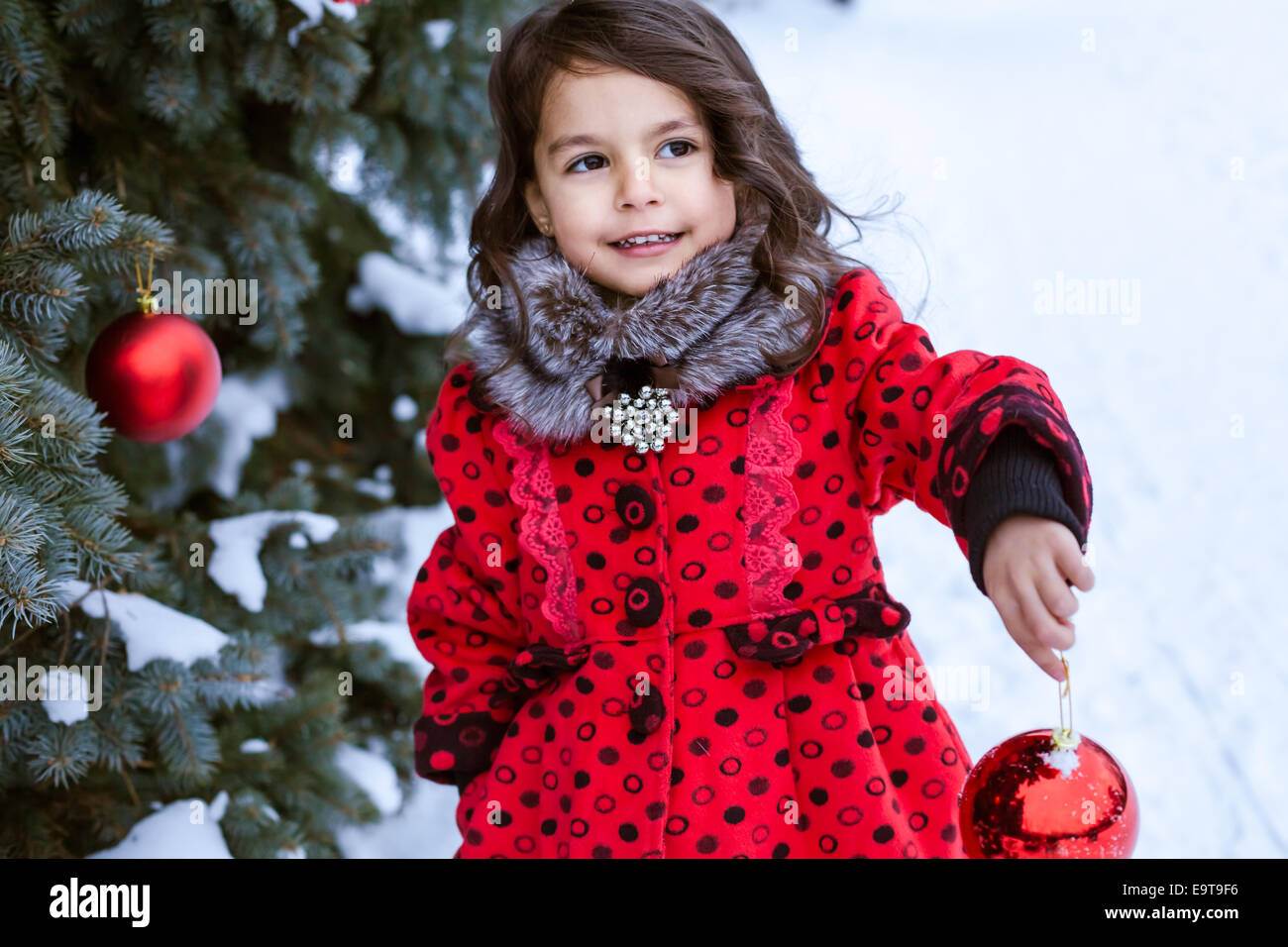Little girl decorating Christmas tree outside Stock Photo - Alamy