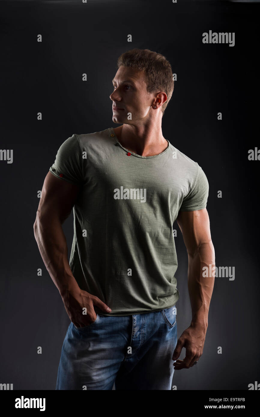 Handsome muscular fit young man on dark background looking to a side ...