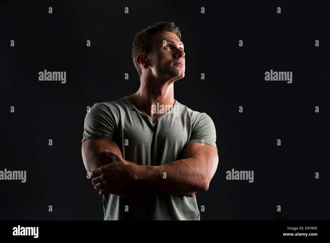 Handsome muscular fit young man on dark background looking up, arms ...