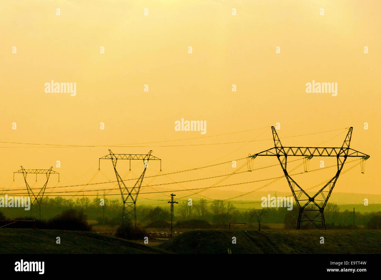 Power line transmission towers lined up on the field at sunset Stock ...