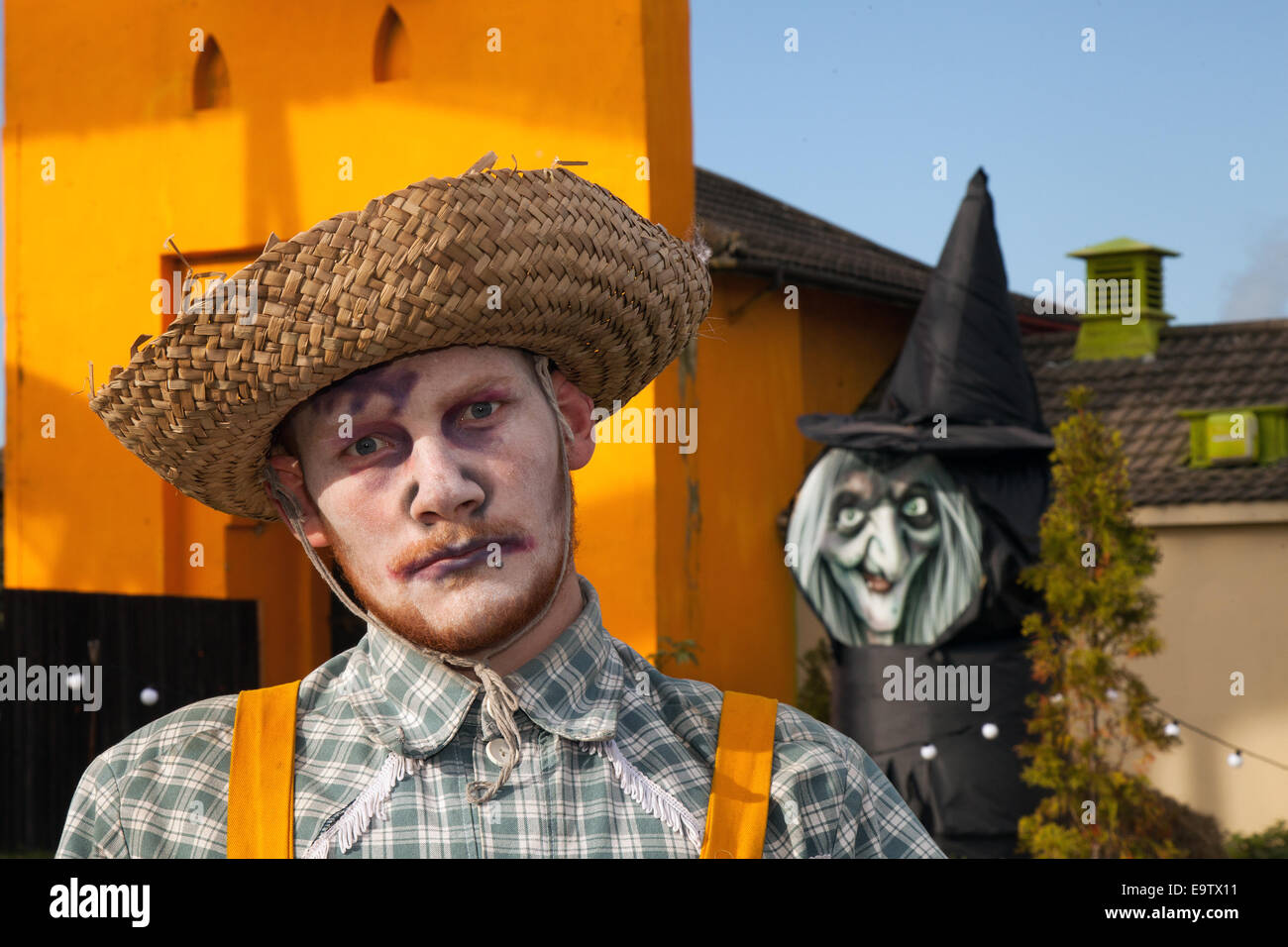 White-faced straw hatted scarecrow man being looked at by a witch at ...
