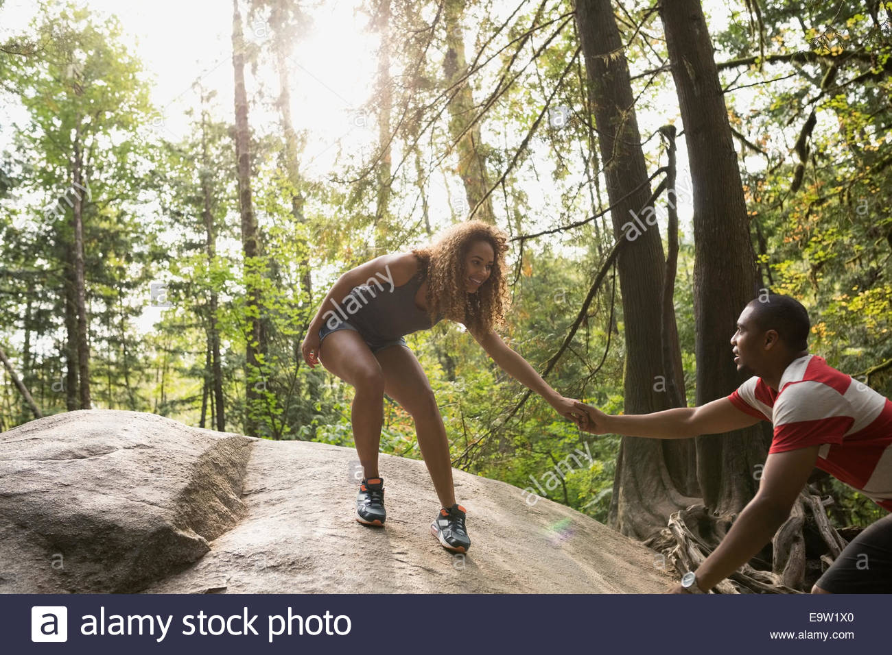 Couple holding hands on large rock in woods Stock Photo - Alamy