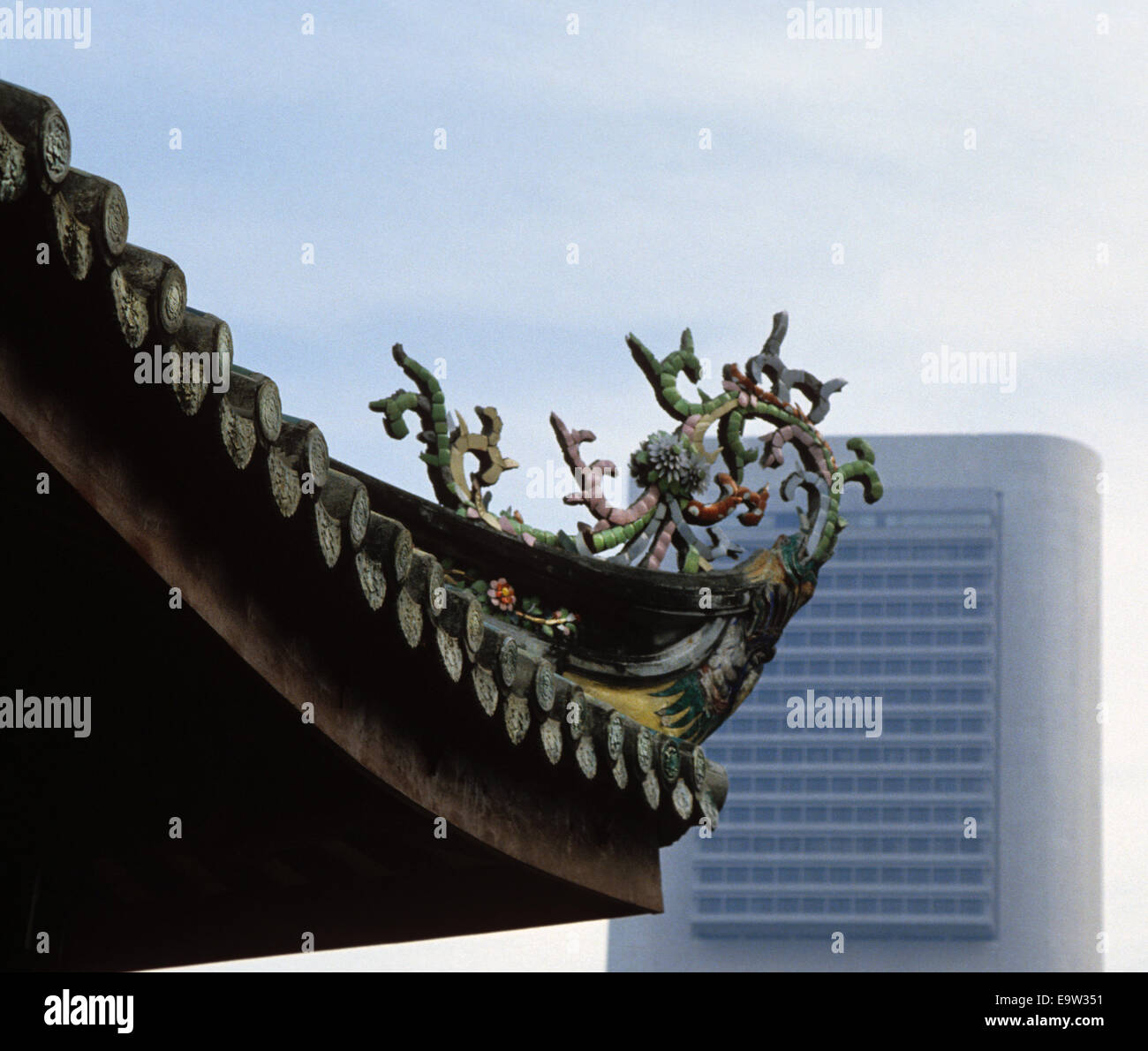 Chinese temple roof decoration, with a modern tower block building ...