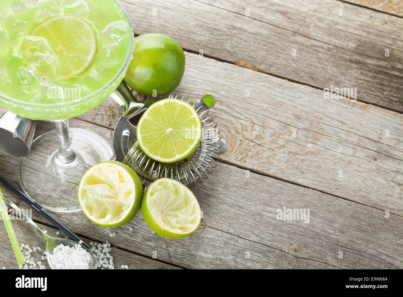 Classic margarita cocktail with salty rim on wooden table with limes ...