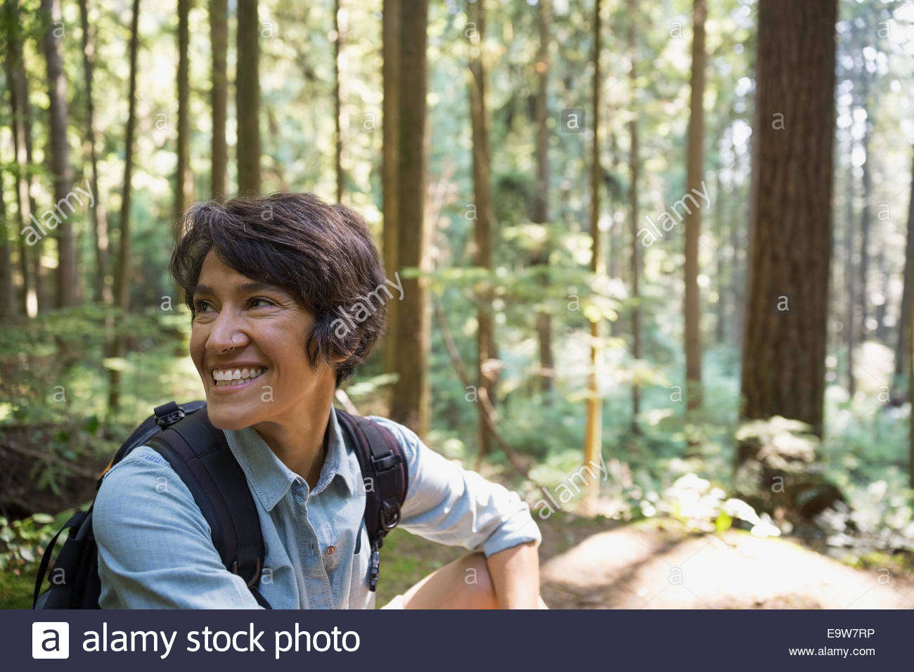 Smiling woman looking over shoulder in woods Stock Photo - Alamy