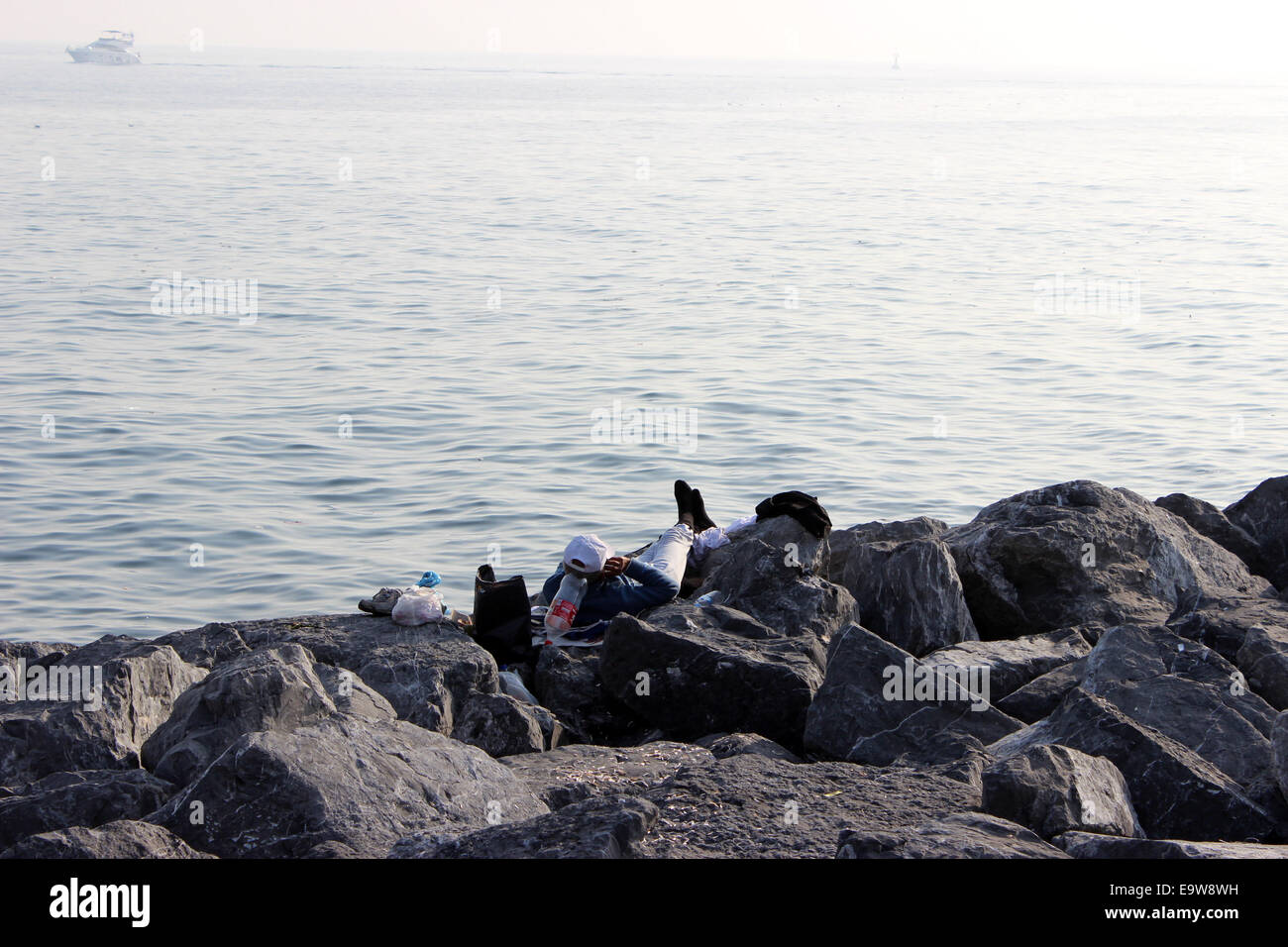 Man sleeping on the rocks near the sea (on the seawall Stock Photo - Alamy