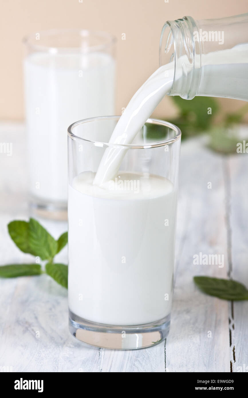 A glass is filled from a bottle of milk Stock Photo - Alamy
