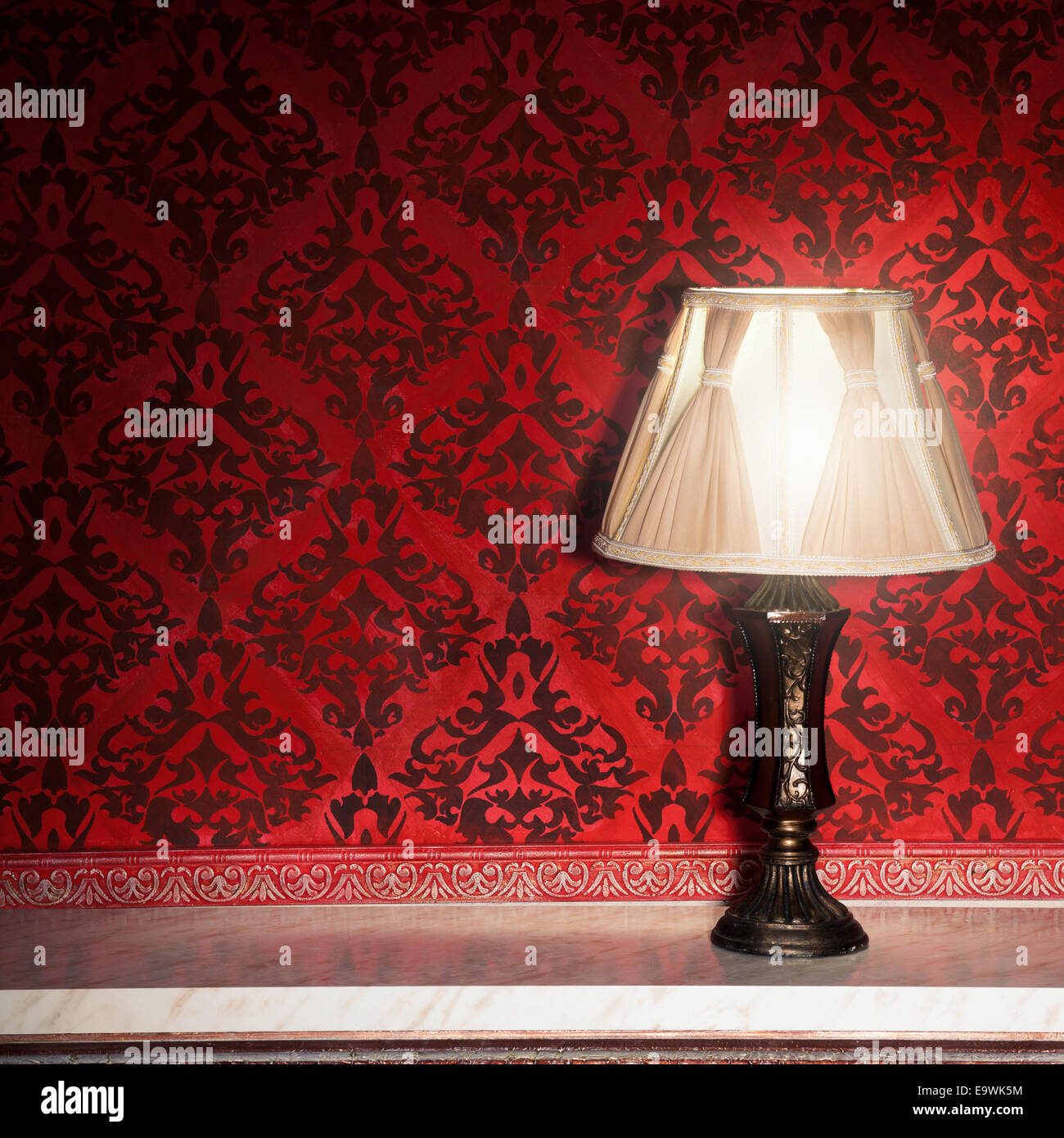 Vintage lamp on old fireplace in room with red rocco pattern. Luxury ...