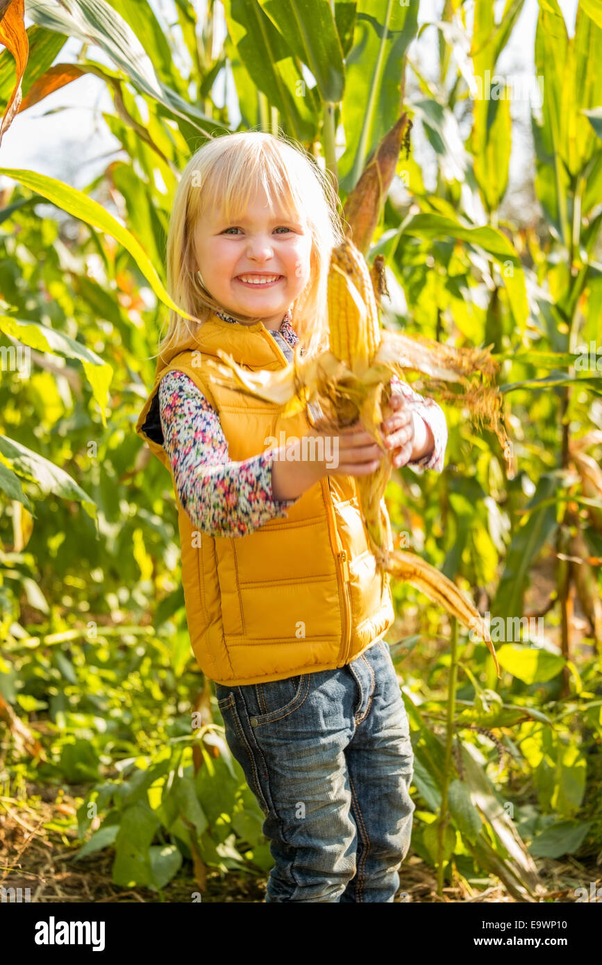 Portrait of smiling child showing corn while in cornfield Stock Photo ...