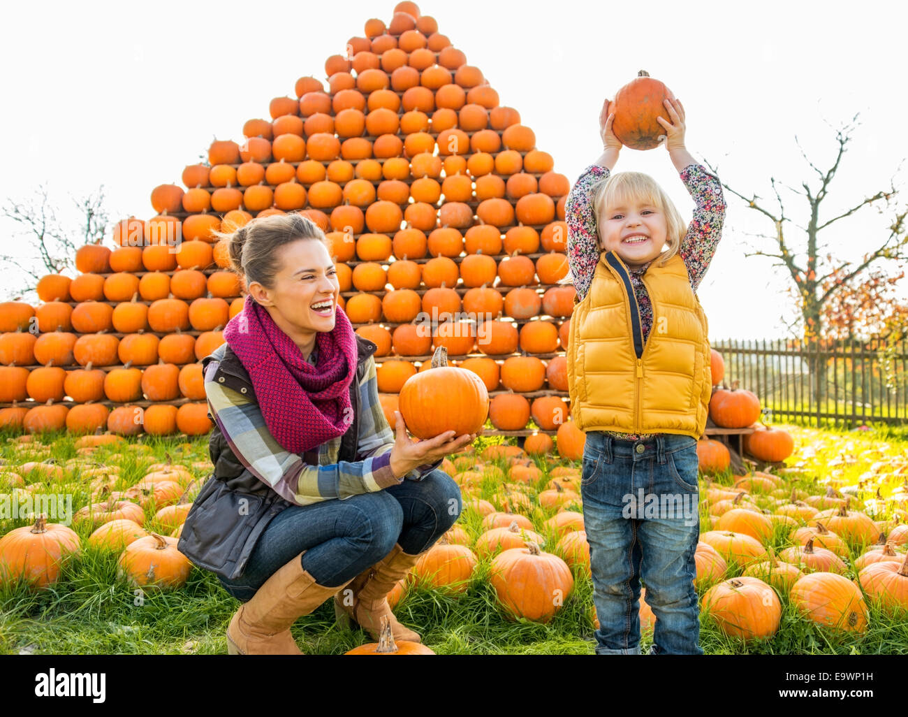 Portrait of happy mother and child pumpkin in front of pumpkin piramide ...