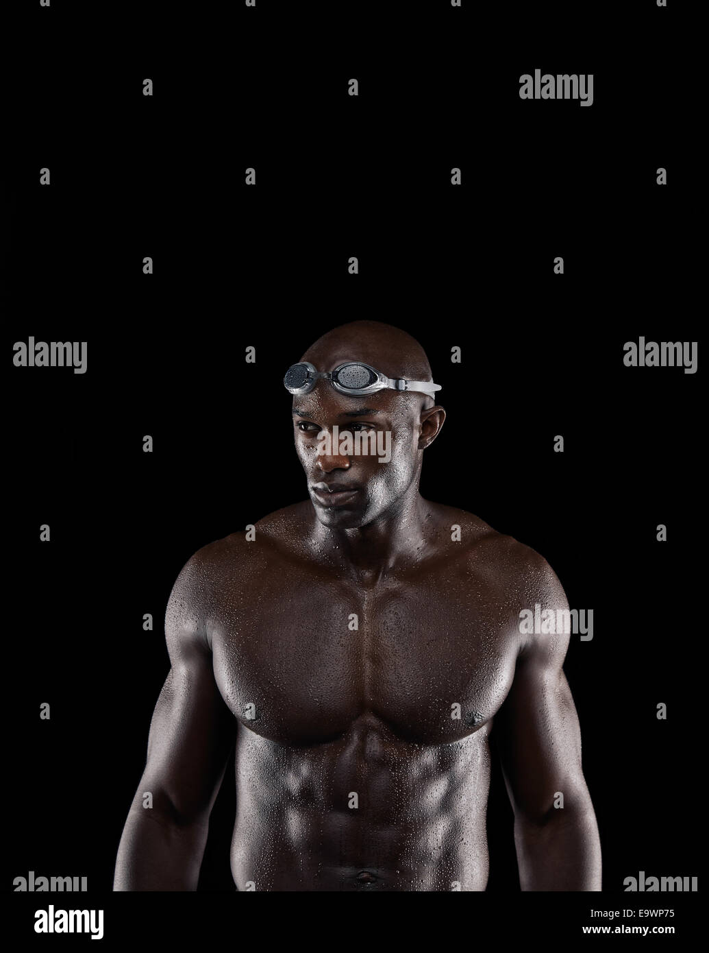 Studio shot of a fit young swimmer against black background. Muscular ...