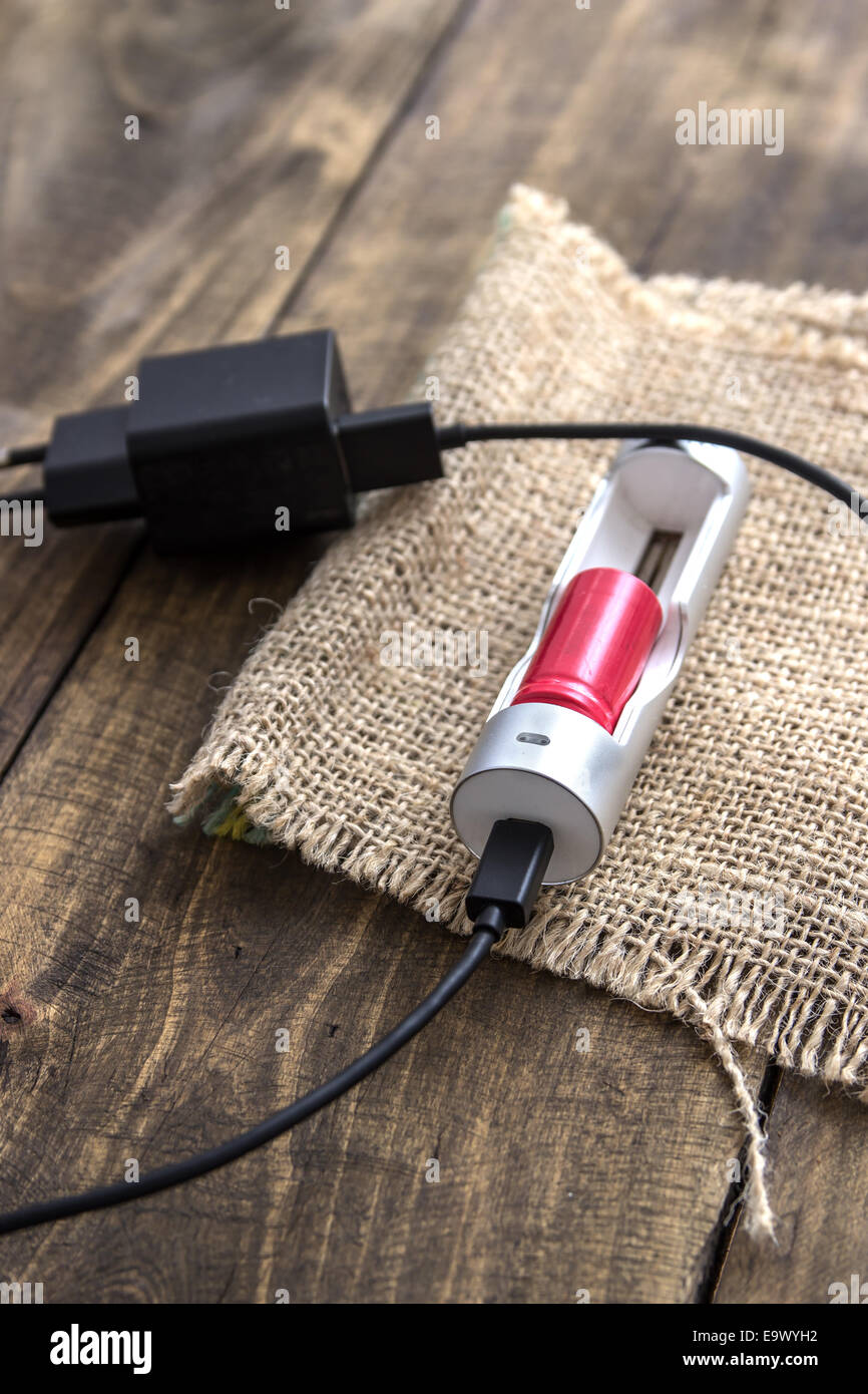 Battery charger with battery on wooden table Stock Photo - Alamy