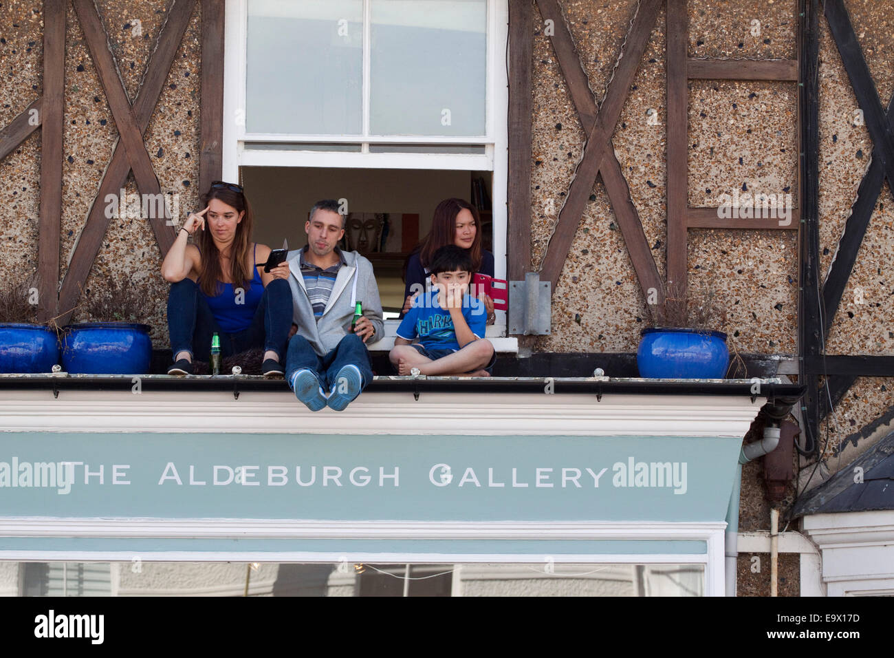 A mixed family group watch a parade from a window and ledge Stock Photo ...