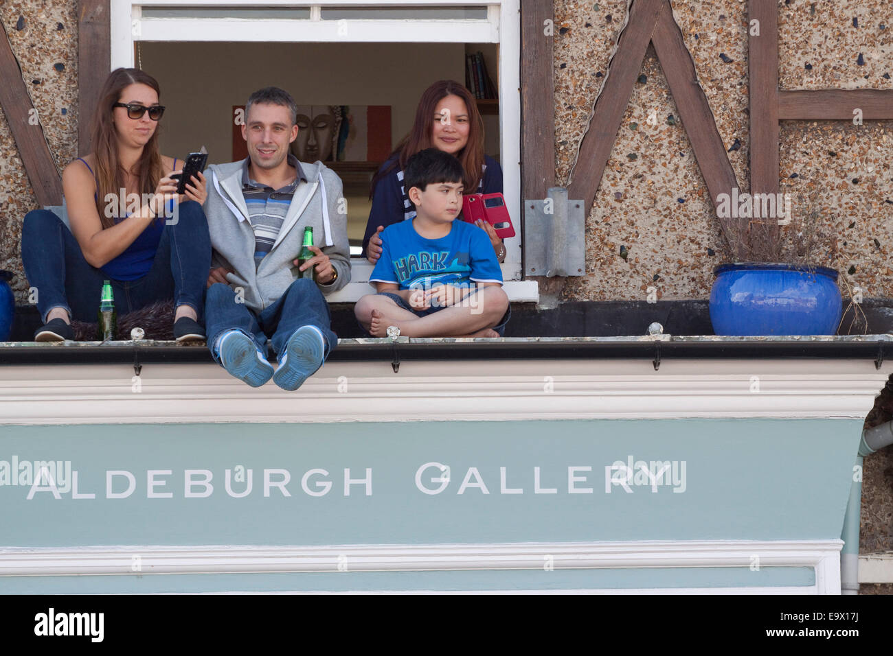 A mixed family group watch a parade from a window and ledge Stock Photo ...