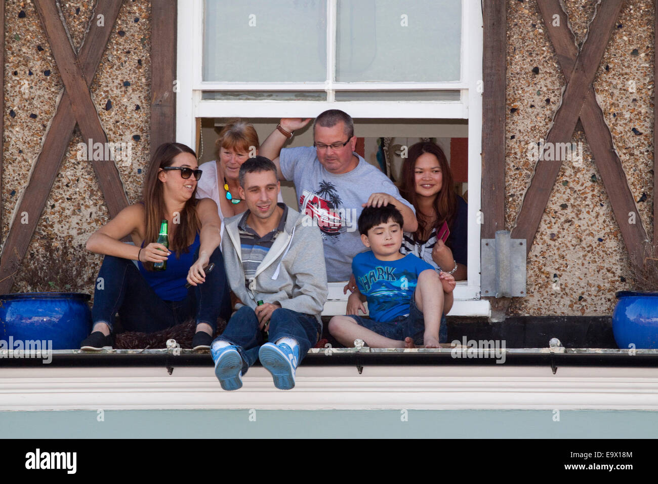 A mixed family group watch a parade from a window and ledge Stock Photo ...