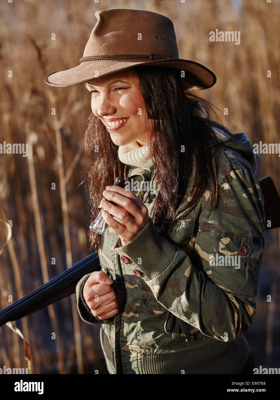 Waterfowl hunting, smiling female hunter carry a shotgun and she use a ...