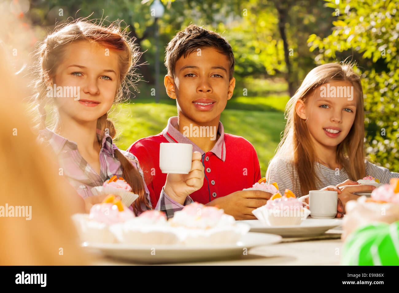Group of diverse looking kids sit outside at table Stock Photo - Alamy