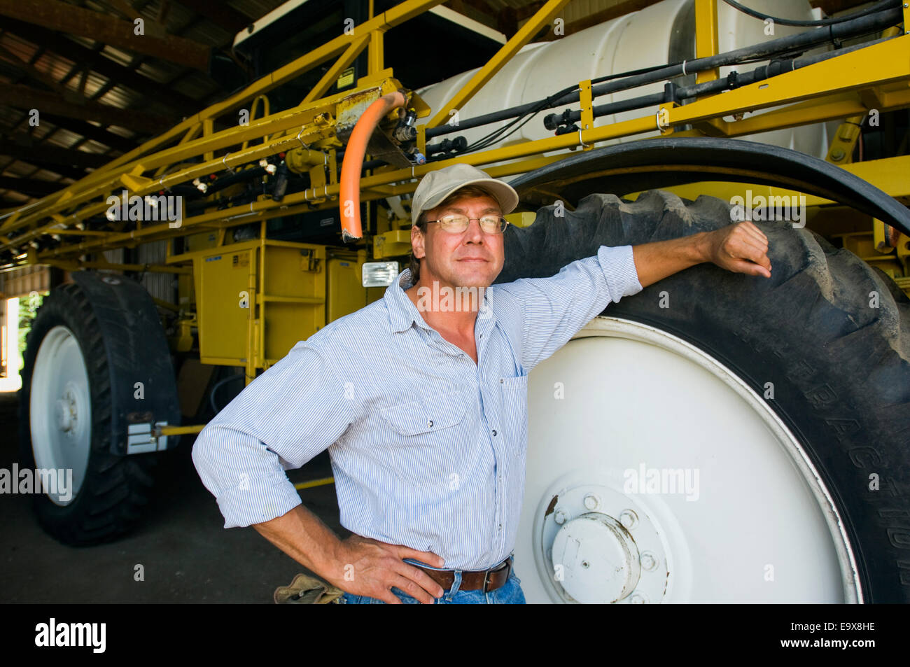 Agriculture - A farmer poses in his farm’s equipment shed with a ...