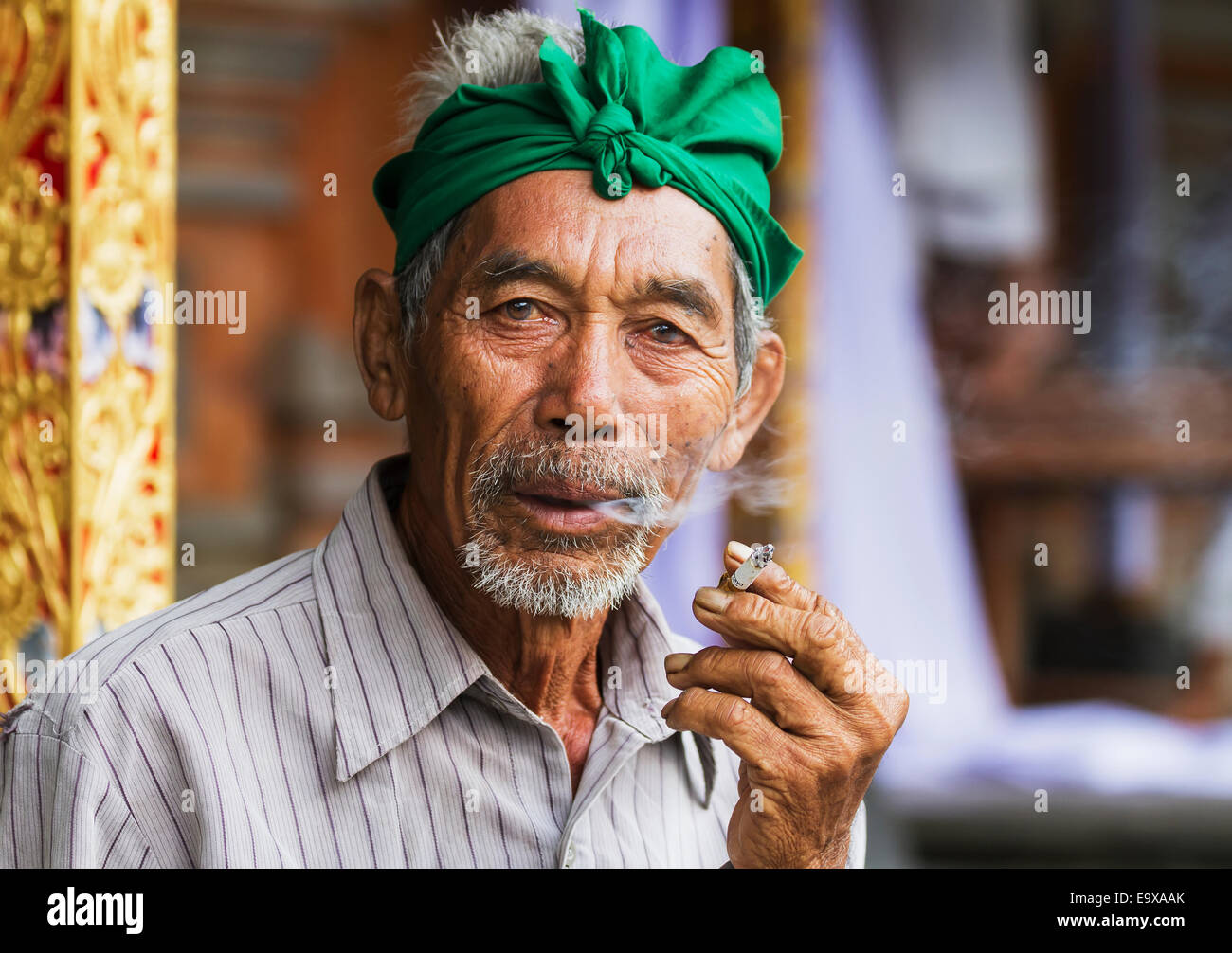 Balinese man smoking a cigarette at Tiirta Empul Temple, Tampaksiring ...