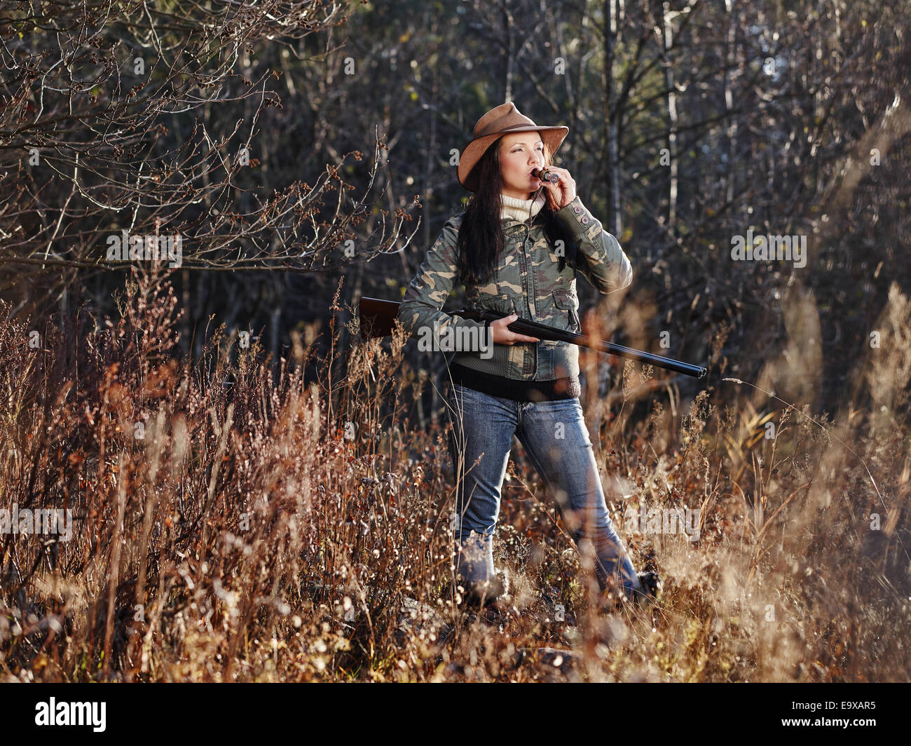 Waterfowl hunting, the female hunter carry a shotgun and she use a duck ...