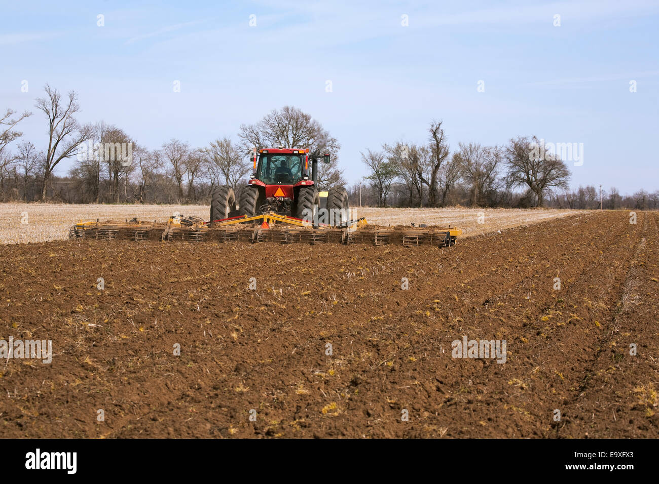 A Case IH tractor and field implement prepare a field in late Spring ...