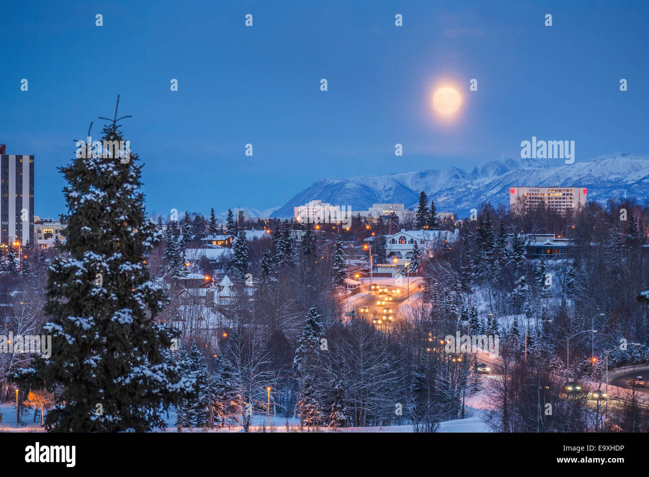 A full moon rises above the Anchorage skyline and Chugach Mountains at ...