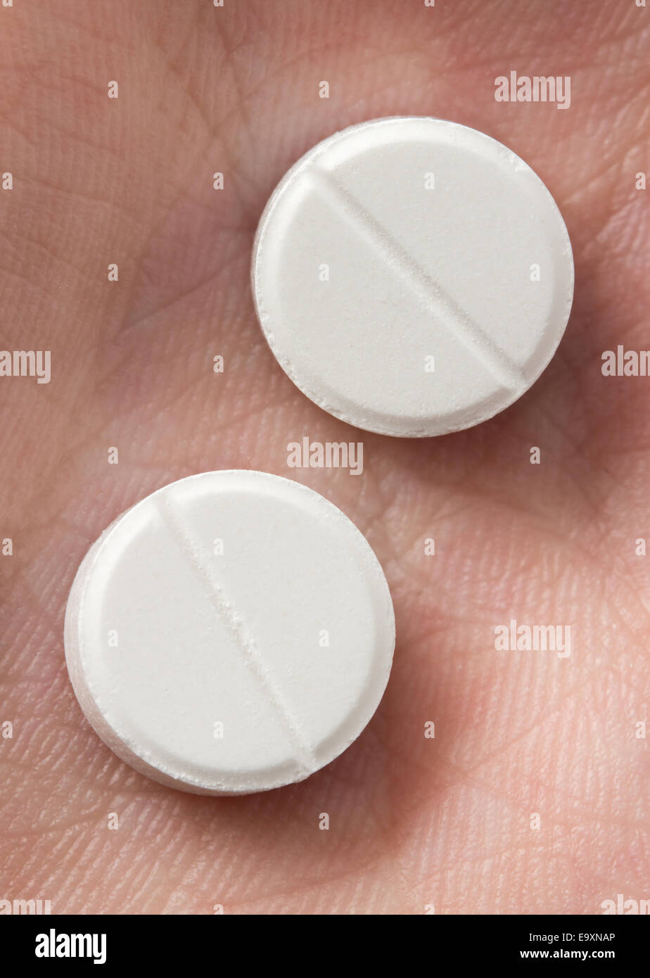 Two pills closeup held in the hand Stock Photo - Alamy