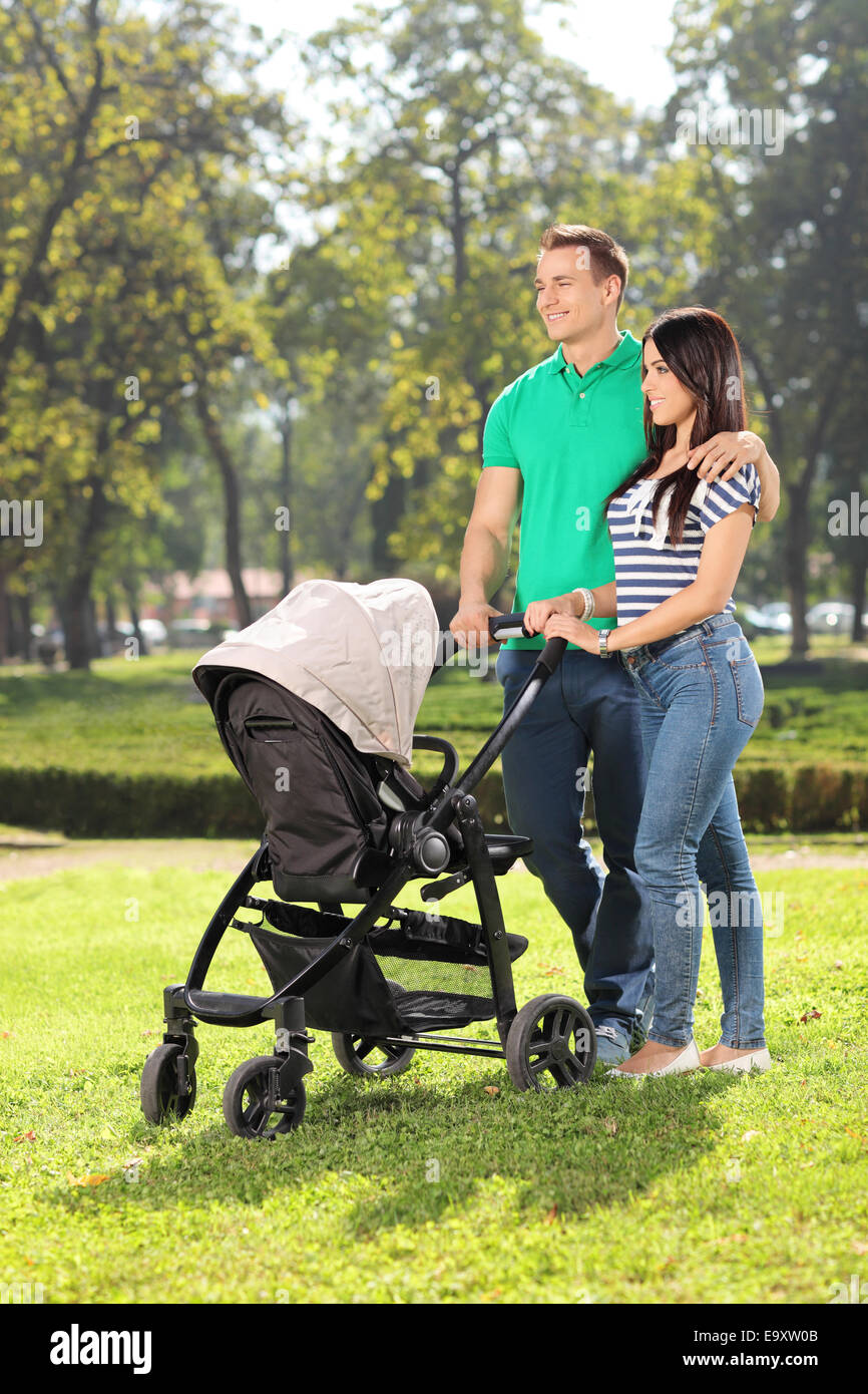 Vertical shot of young parents pushing a baby stroller in a park Stock ...