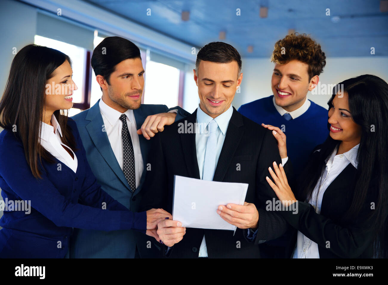 Happy colleagues congratulating businessman in office Stock Photo - Alamy