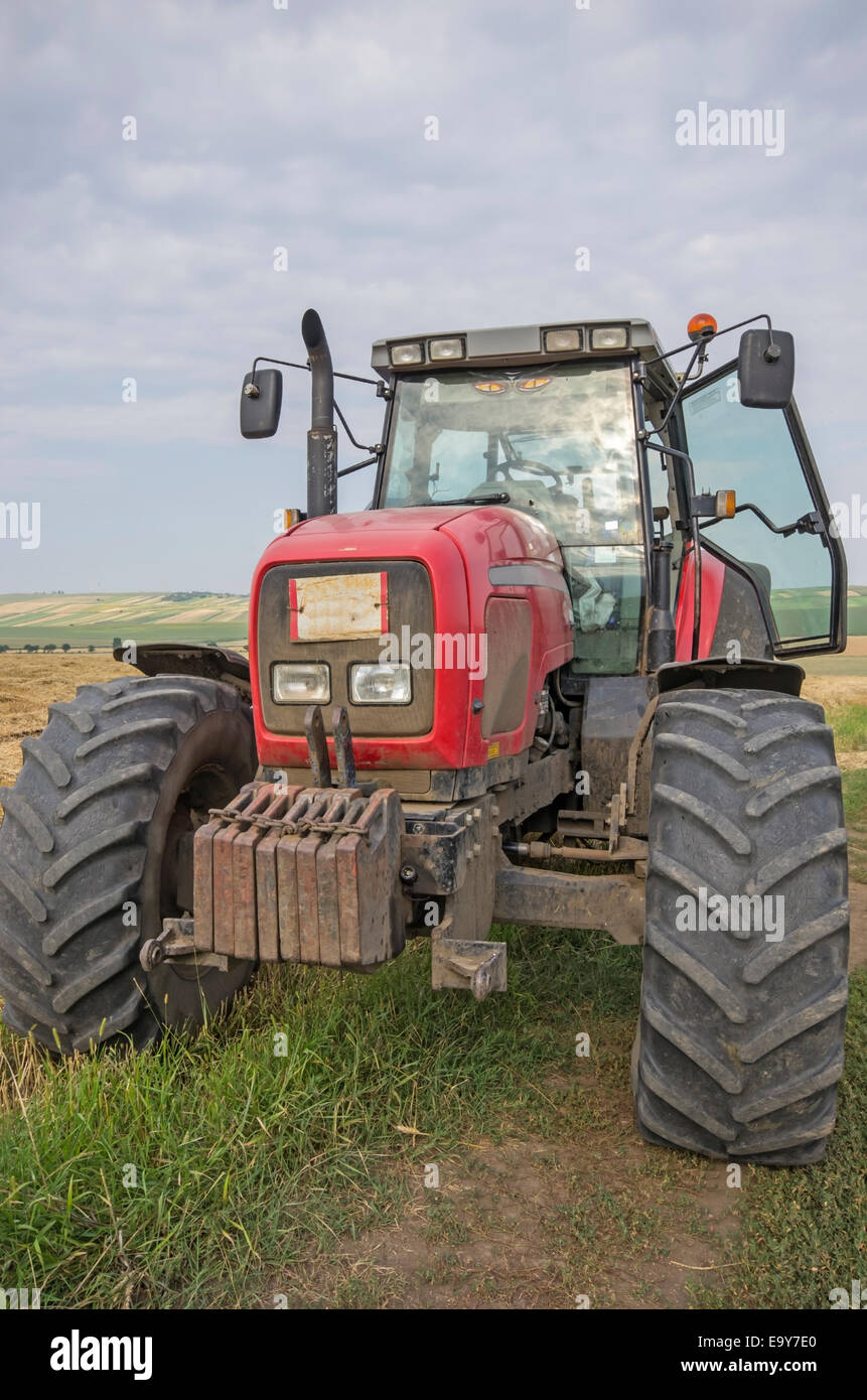 Agriculture farming red tractor on a field Stock Photo - Alamy