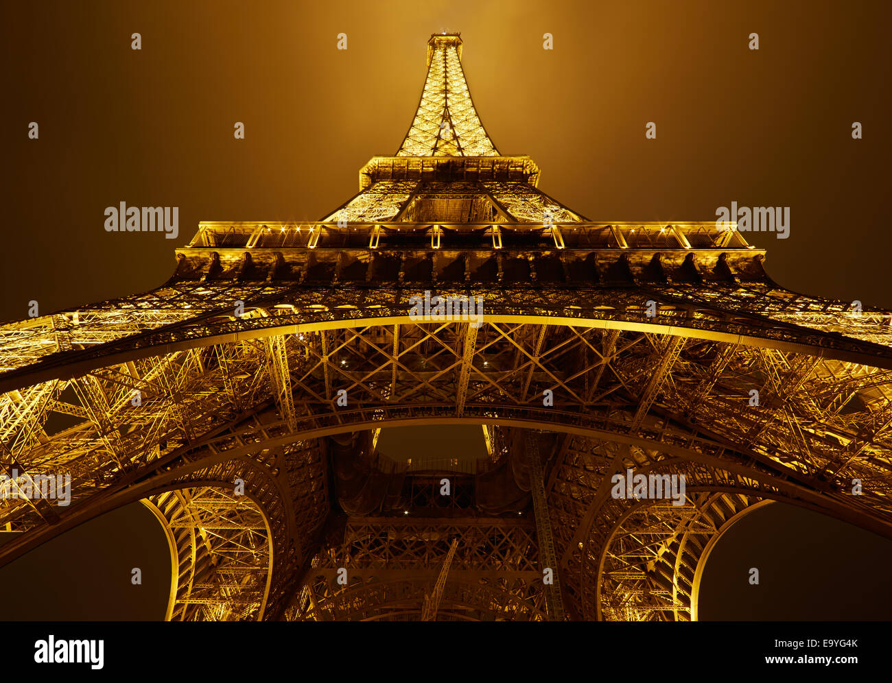 Eiffel tower with golden illumination in Paris at night, low angle view ...