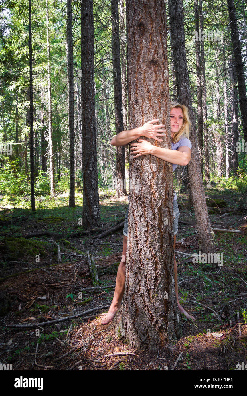 pretty woman smiling hugging a small Douglas fur tree in the oregon ...