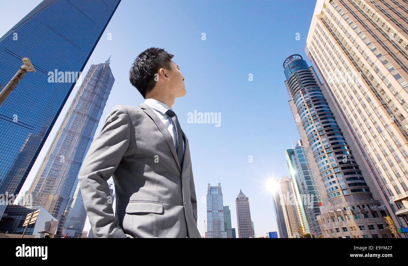 Young business man standing buildings in the middle Stock Photo - Alamy