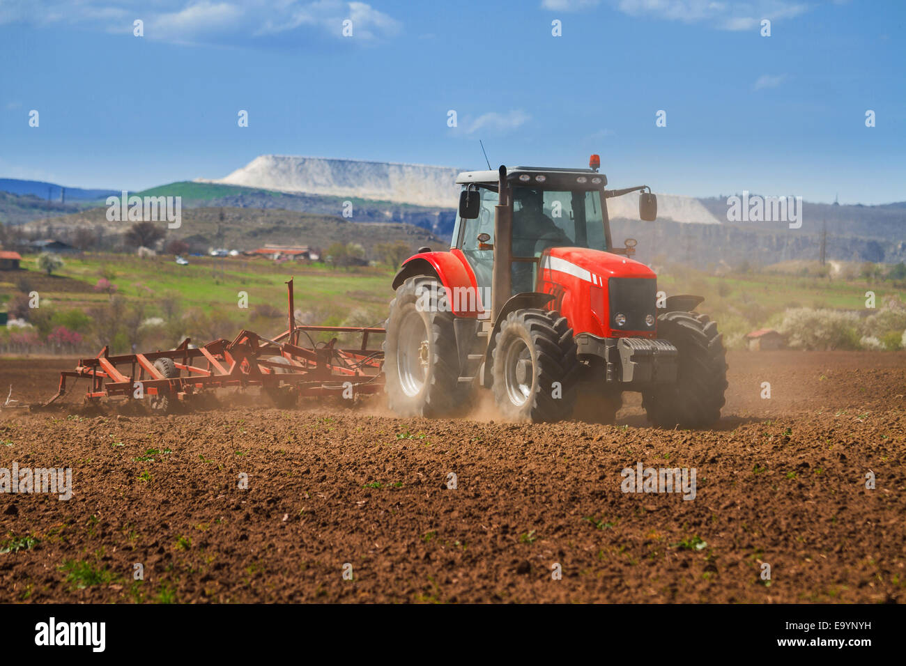 Brand new red tractor on the field working Stock Photo - Alamy