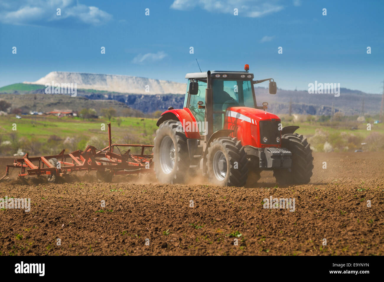 Brand new red tractor on the field working Stock Photo - Alamy