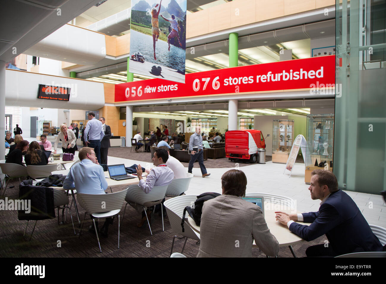 Workers drinking coffee and working on devices inside Vodafone UK ...