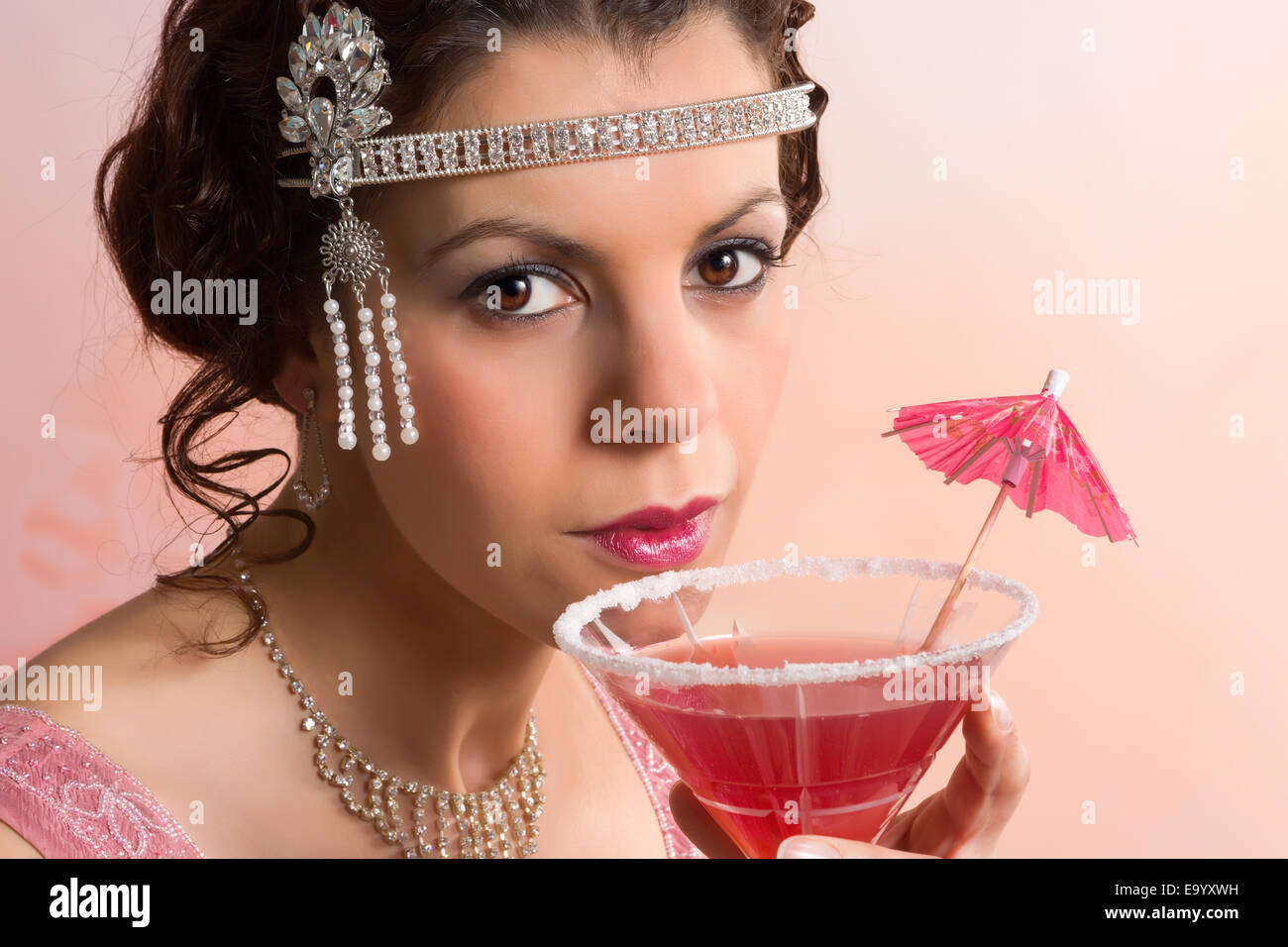 Beautiful young vintage 1920s woman with headband and flapper dress drinking a cocktail Stock ...