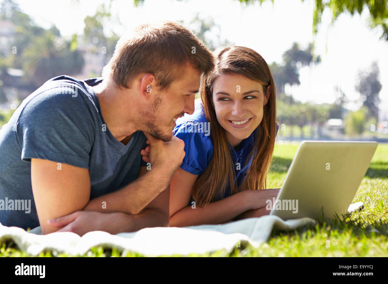 Couple using laptop in park Stock Photo - Alamy