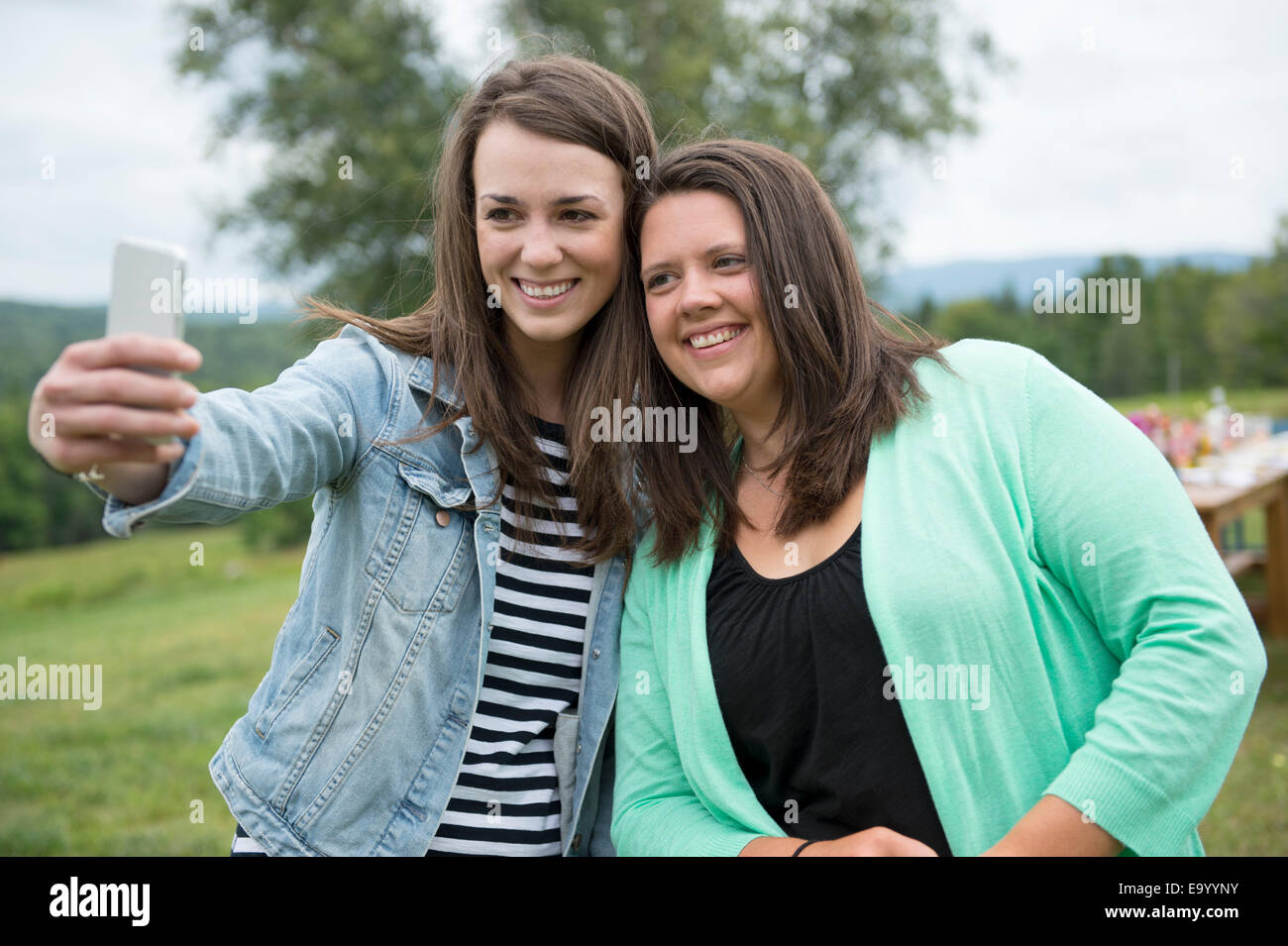 Two female friends taking self portrait using smartphone, outdoors ...