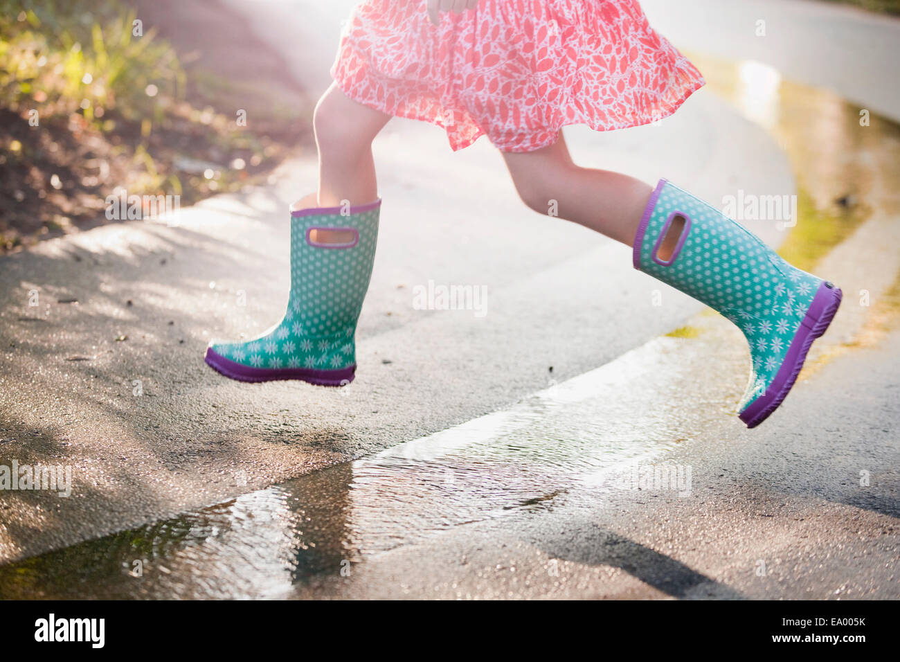 Waist down view of girl jumping puddles on rainy street Stock Photo - Alamy