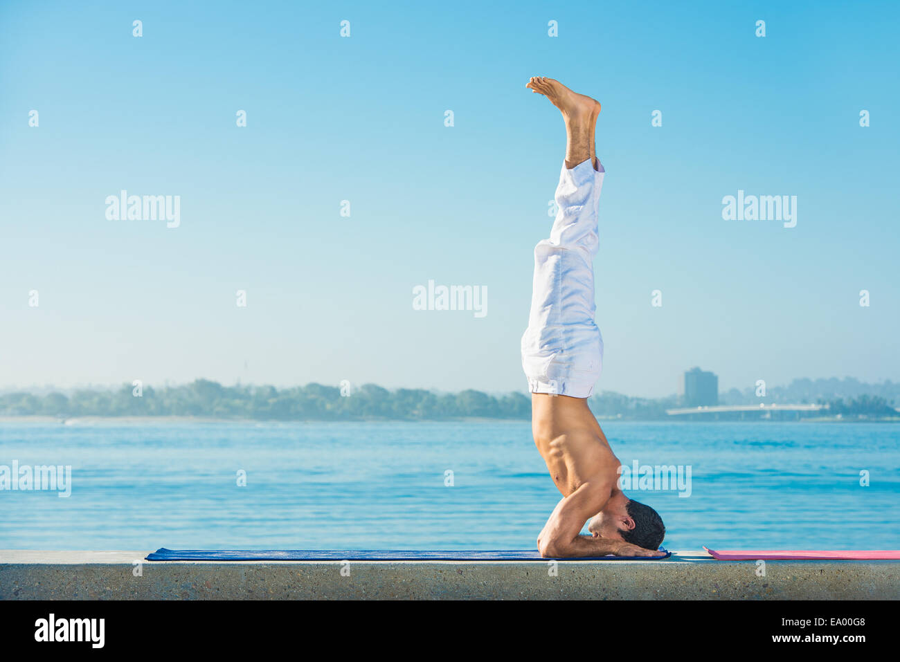 Young man practicing upside down yoga position at Pacific beach, San ...