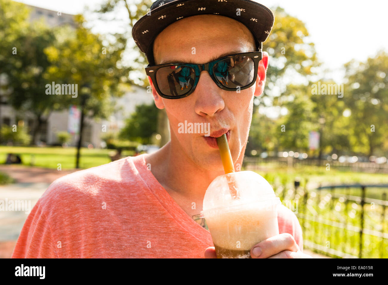 Portrait of young man drinking frappe in park Stock Photo - Alamy