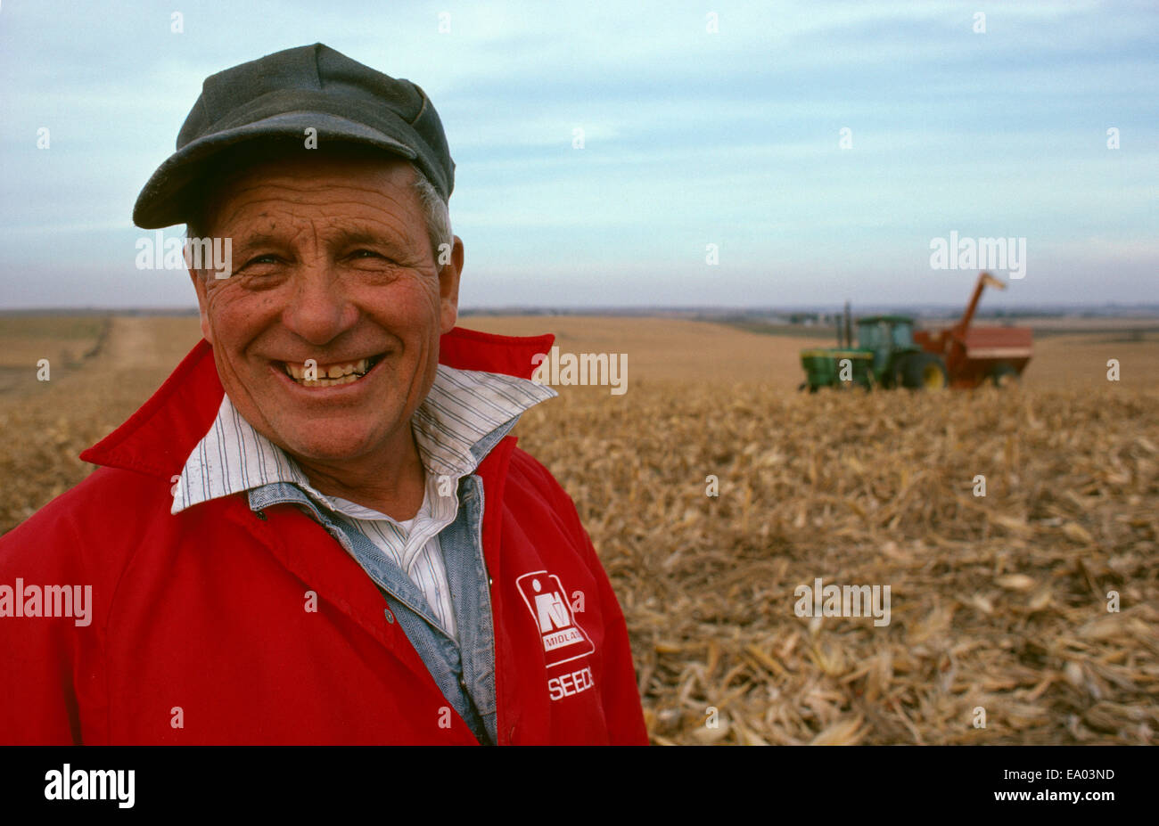 Agriculture - A farmer with a big smile stands in a corn field during ...
