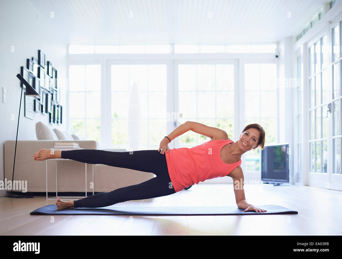 Mid adult woman practicing yoga position in living room Stock Photo - Alamy