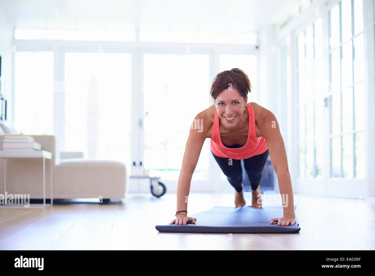 Mid adult woman doing press ups in living room Stock Photo - Alamy