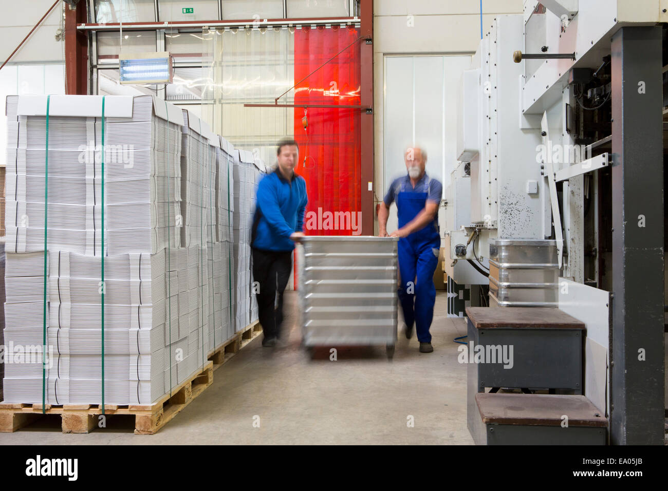 Factory workers moving containers of cardboard Stock Photo - Alamy