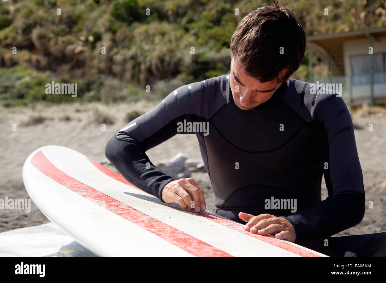 Young adult male surfer waxing board Stock Photo - Alamy