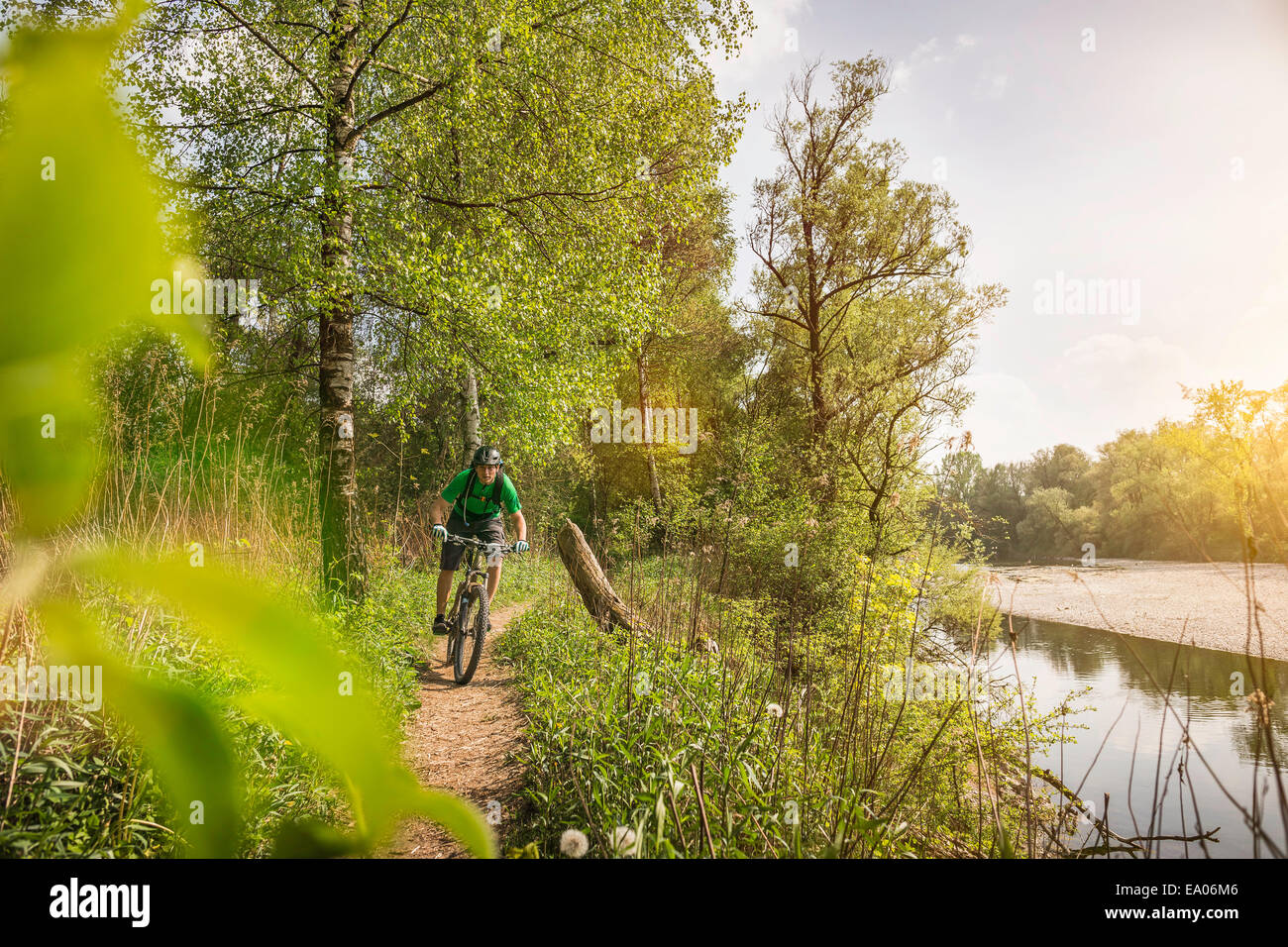 Young man cycling along riverside path Stock Photo - Alamy